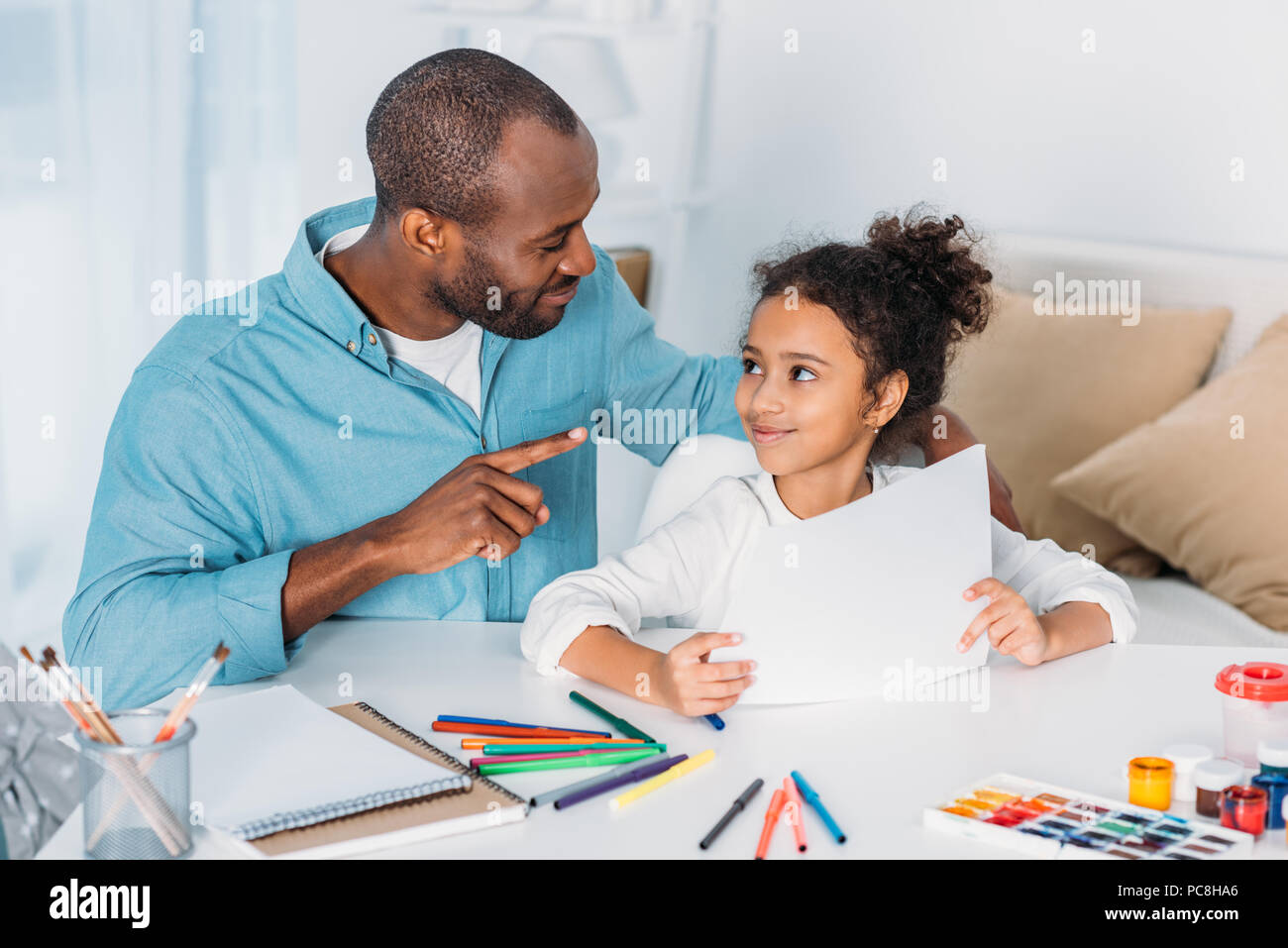 african american father pointing on something and looking at daughter ...