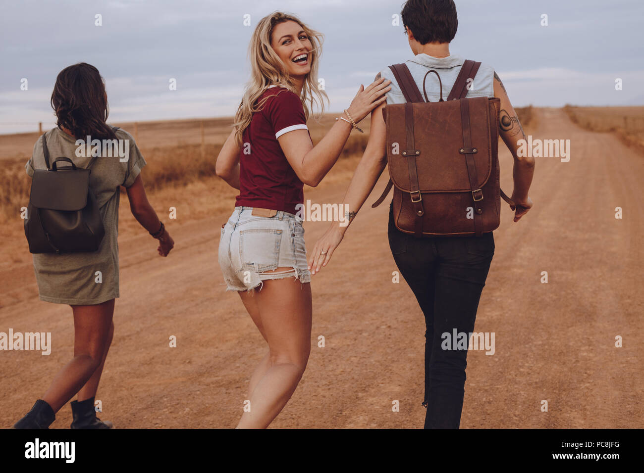 Rear view of three young women having fun while walking down the ...