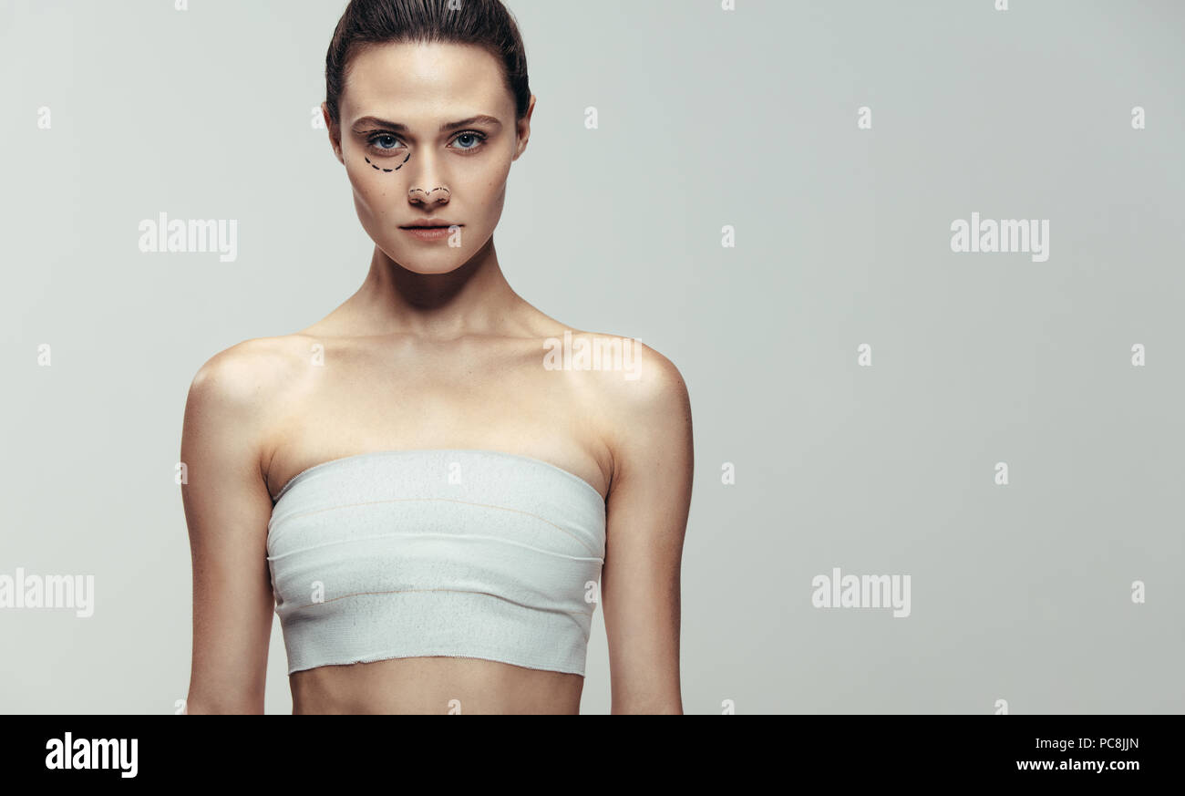 Portrait of beautiful young woman with dotted line on face against grey ...