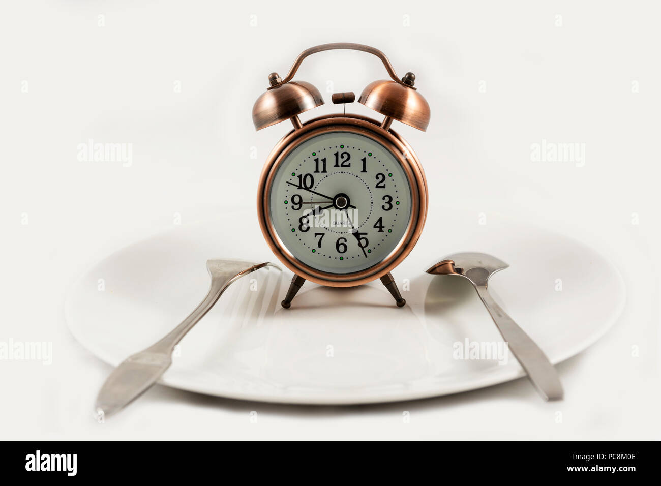 copper look clock with spoon and fork in white background Stock Photo ...