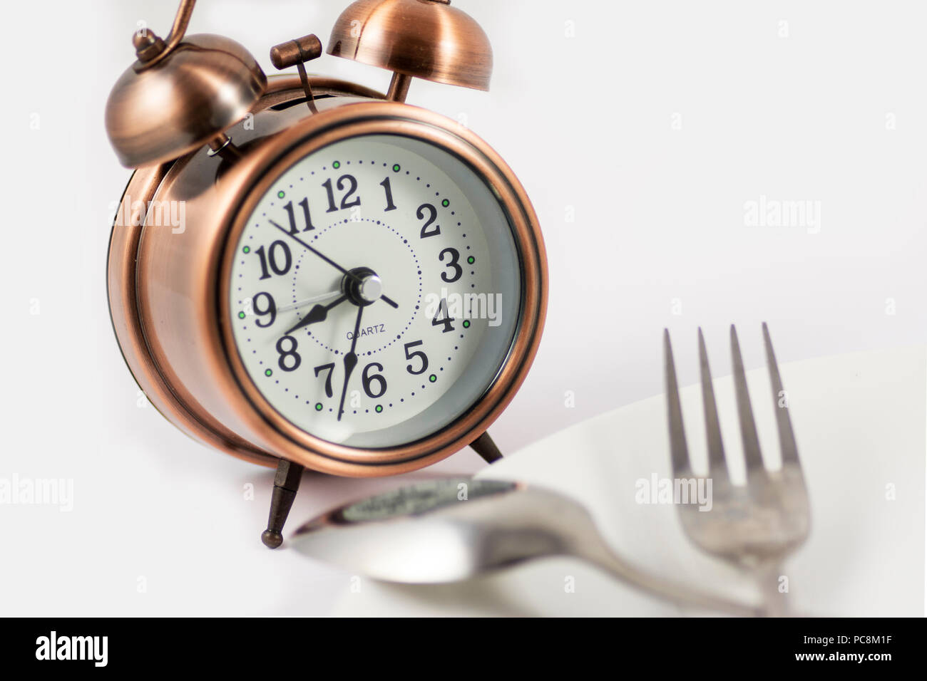 copper look clock with spoon and fork in white background Stock Photo ...