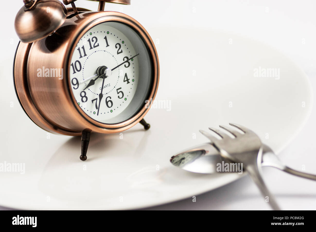 copper look clock with spoon and fork in white background Stock Photo ...