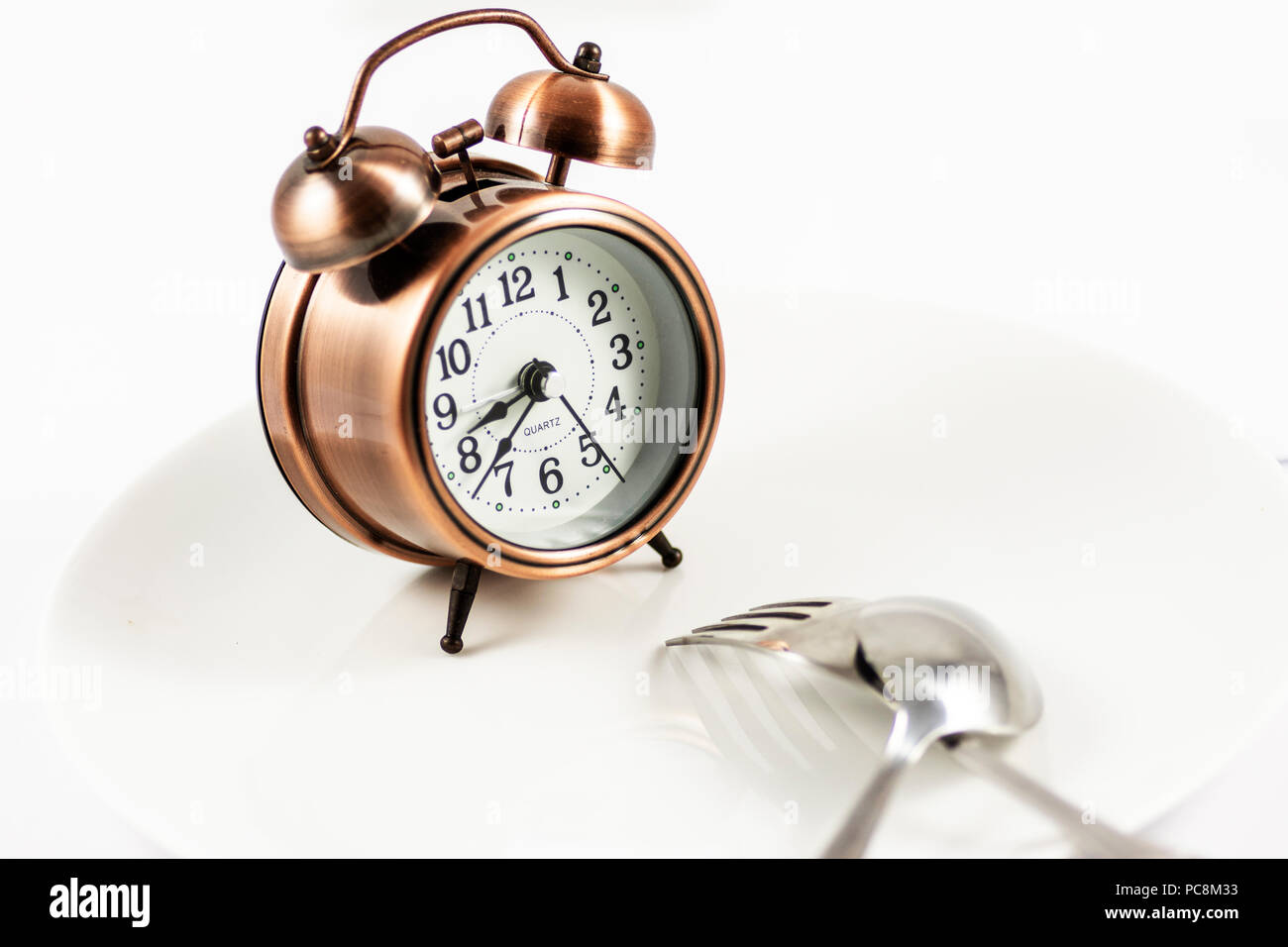 copper look clock with spoon and fork in white background Stock Photo ...