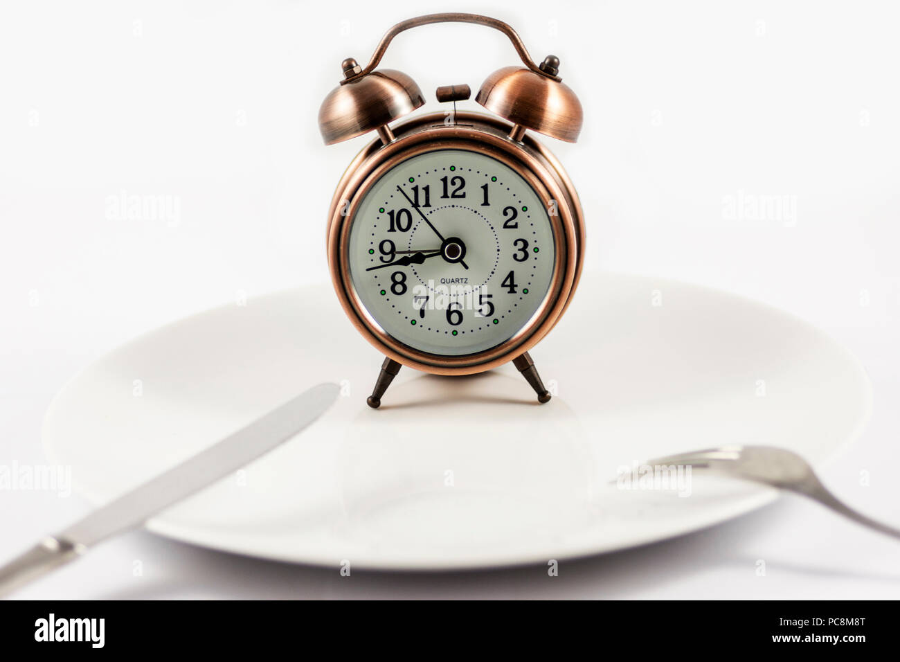 copper look clock with knife and fork in white background Stock Photo ...