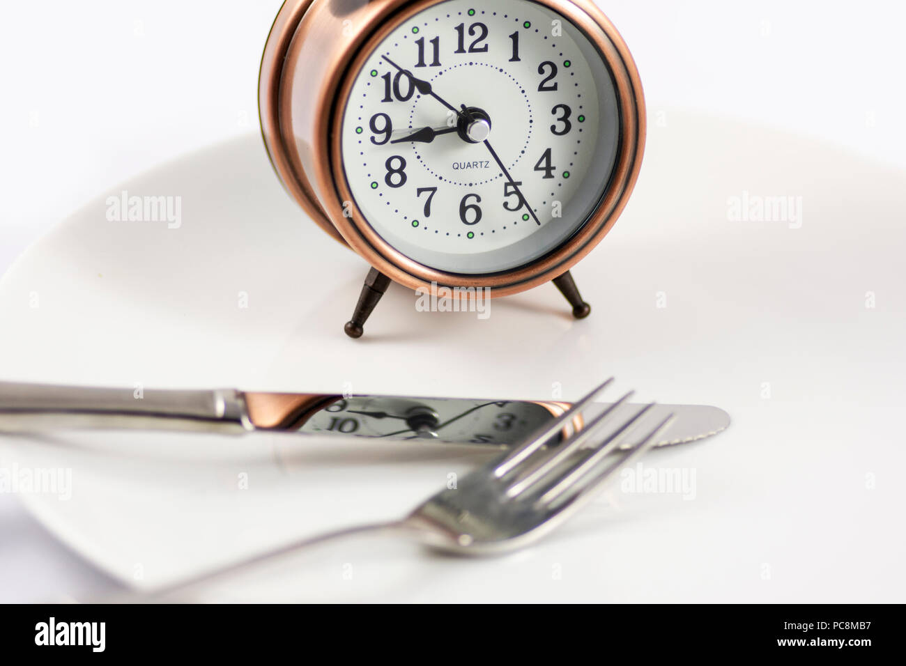 copper look clock with knife and fork in white background Stock Photo ...