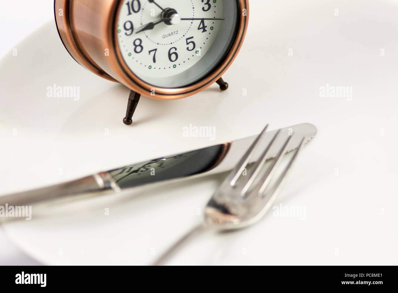 copper look clock with knife and fork in white background Stock Photo ...