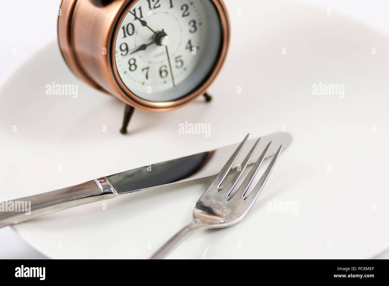 copper look clock with knife and fork in white background Stock Photo ...