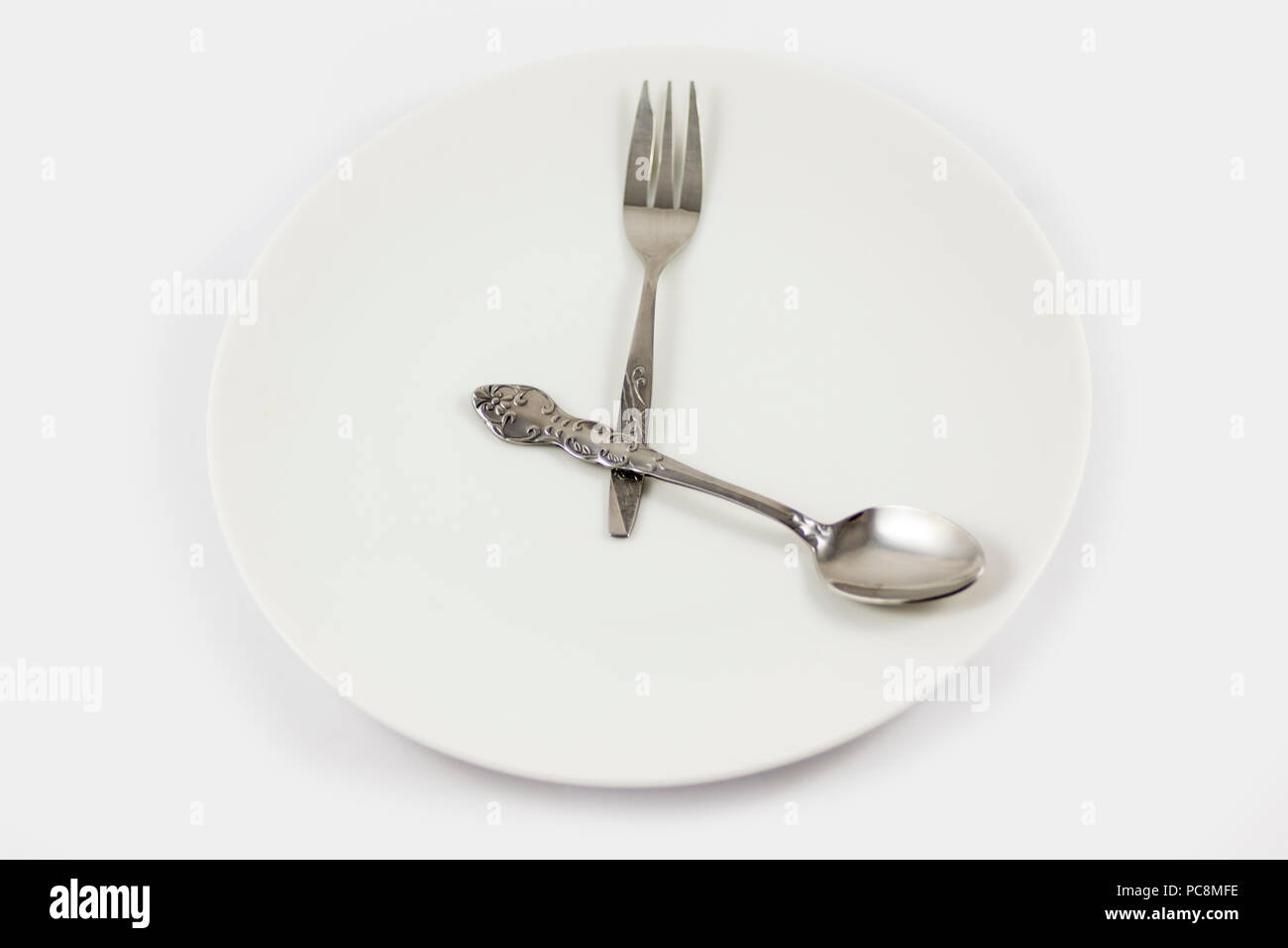 clock looking with spoon and fork in white background Stock Photo - Alamy