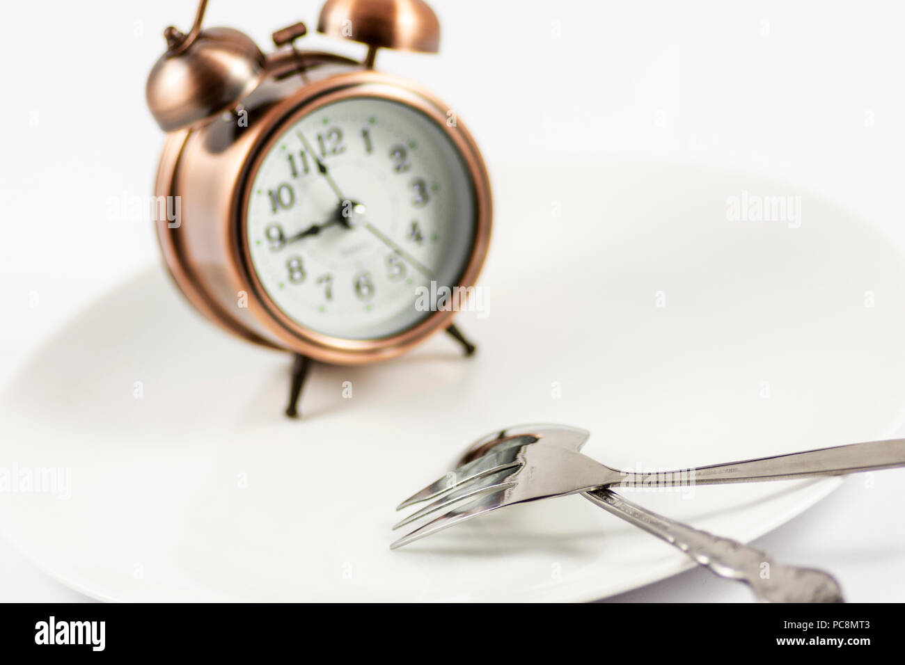 copper look clock with knife and fork in white background Stock Photo ...
