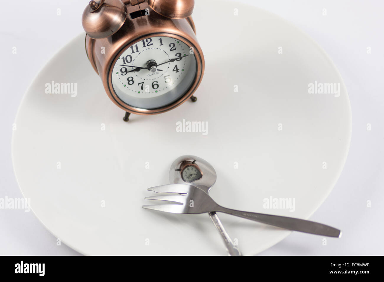 copper look clock with knife and fork in white background Stock Photo ...