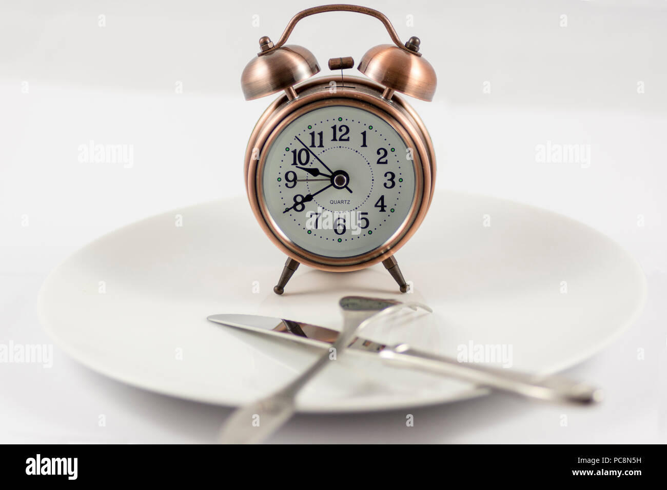 copper look clock with knife and fork in white background Stock Photo ...