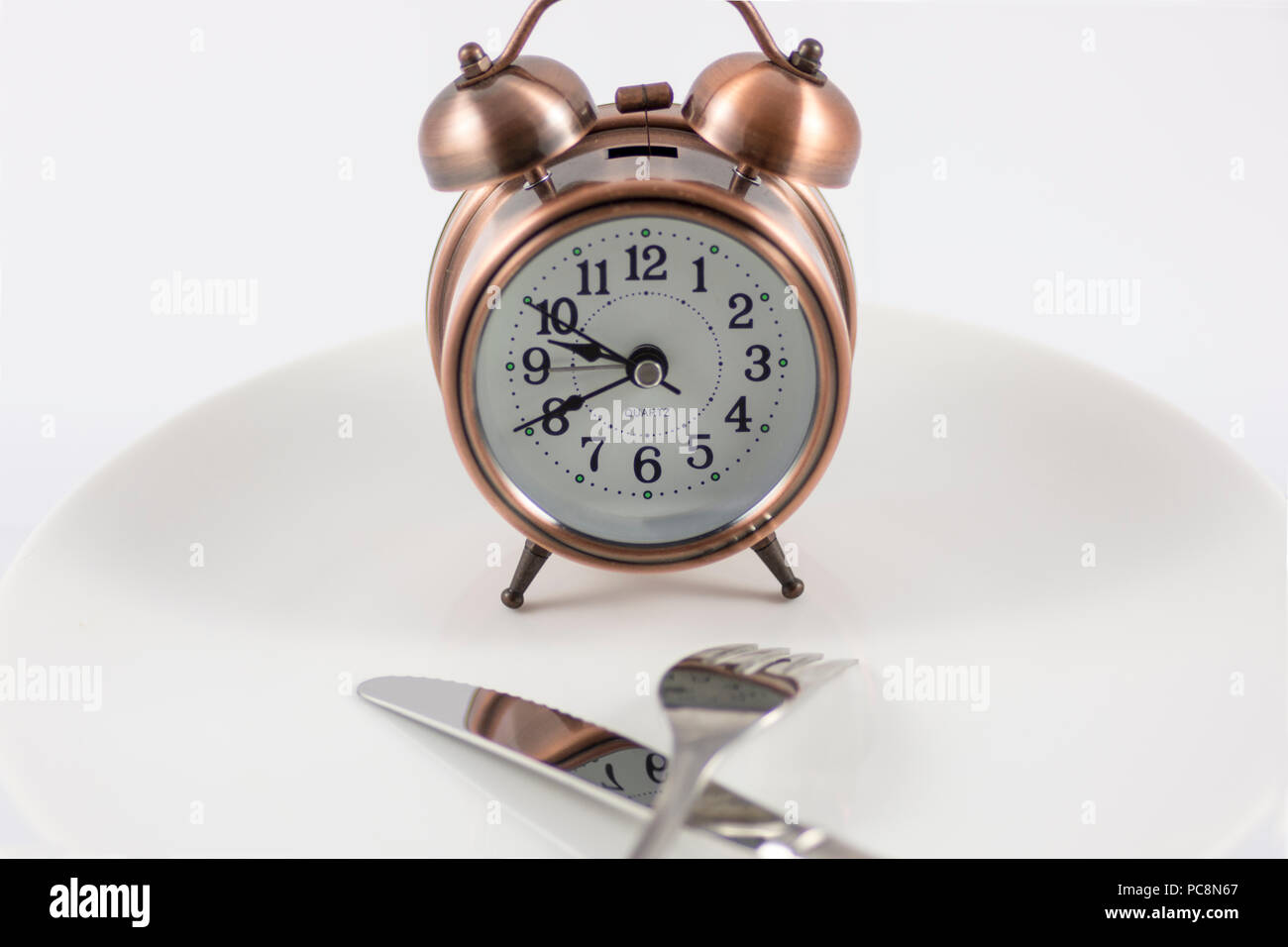 copper look clock with knife and fork in white background Stock Photo ...