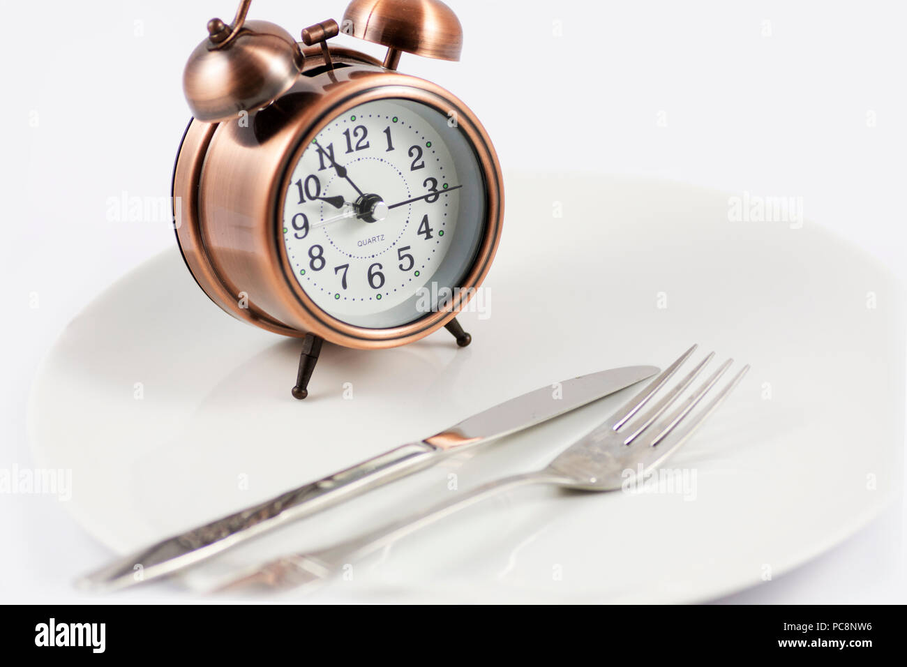 copper look clock with knife and fork in white background Stock Photo ...