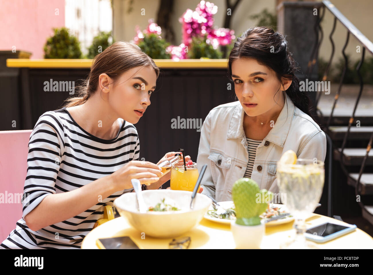 Secret alcohol. Two young women secretly adding alcohol from little ...