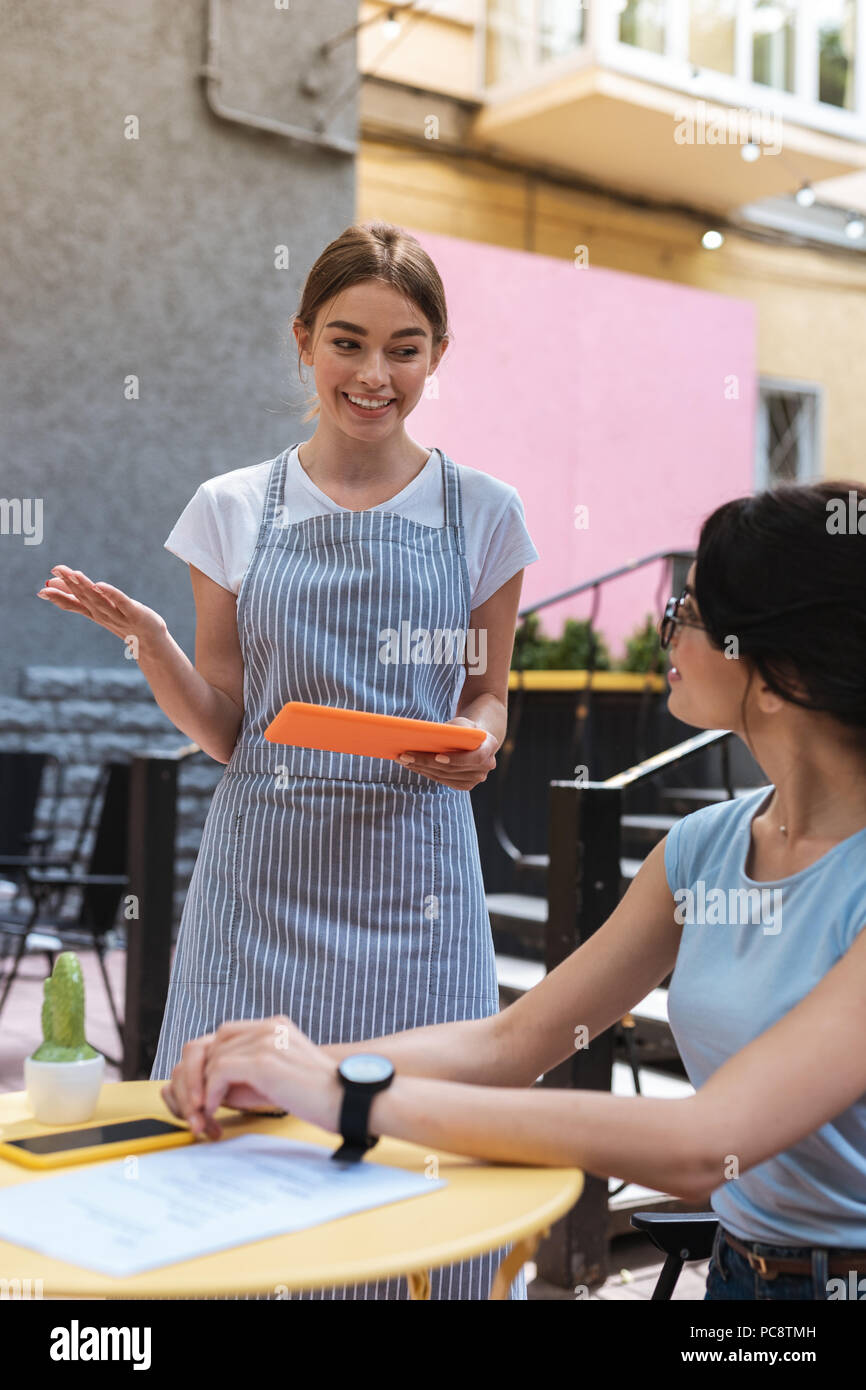 Pleasant waitress. Pleasant smiling waitress receiving an order from ...