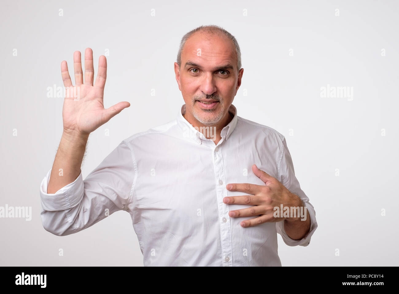 Friendly-looking attractive european man waiving hand in hello gesture ...