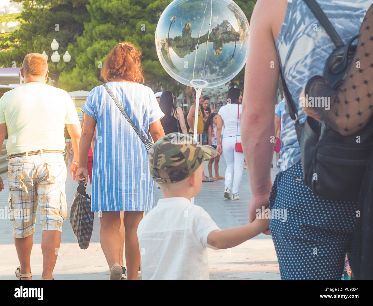 back view of young kid boy walking with balloon in the crowd in the ...