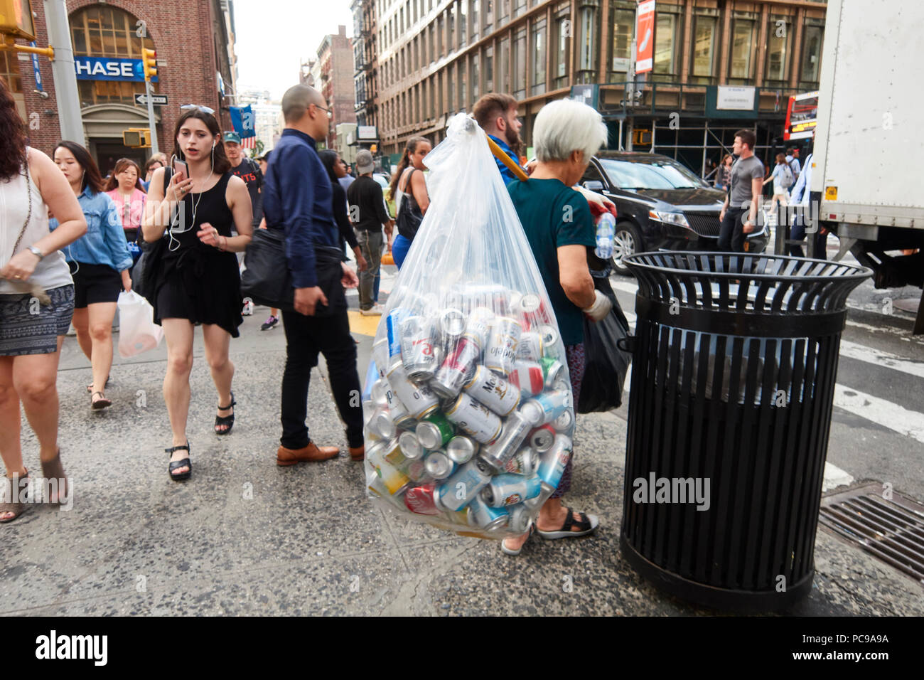 Old lady recollecting empty cans and bottles from street trash bins ...