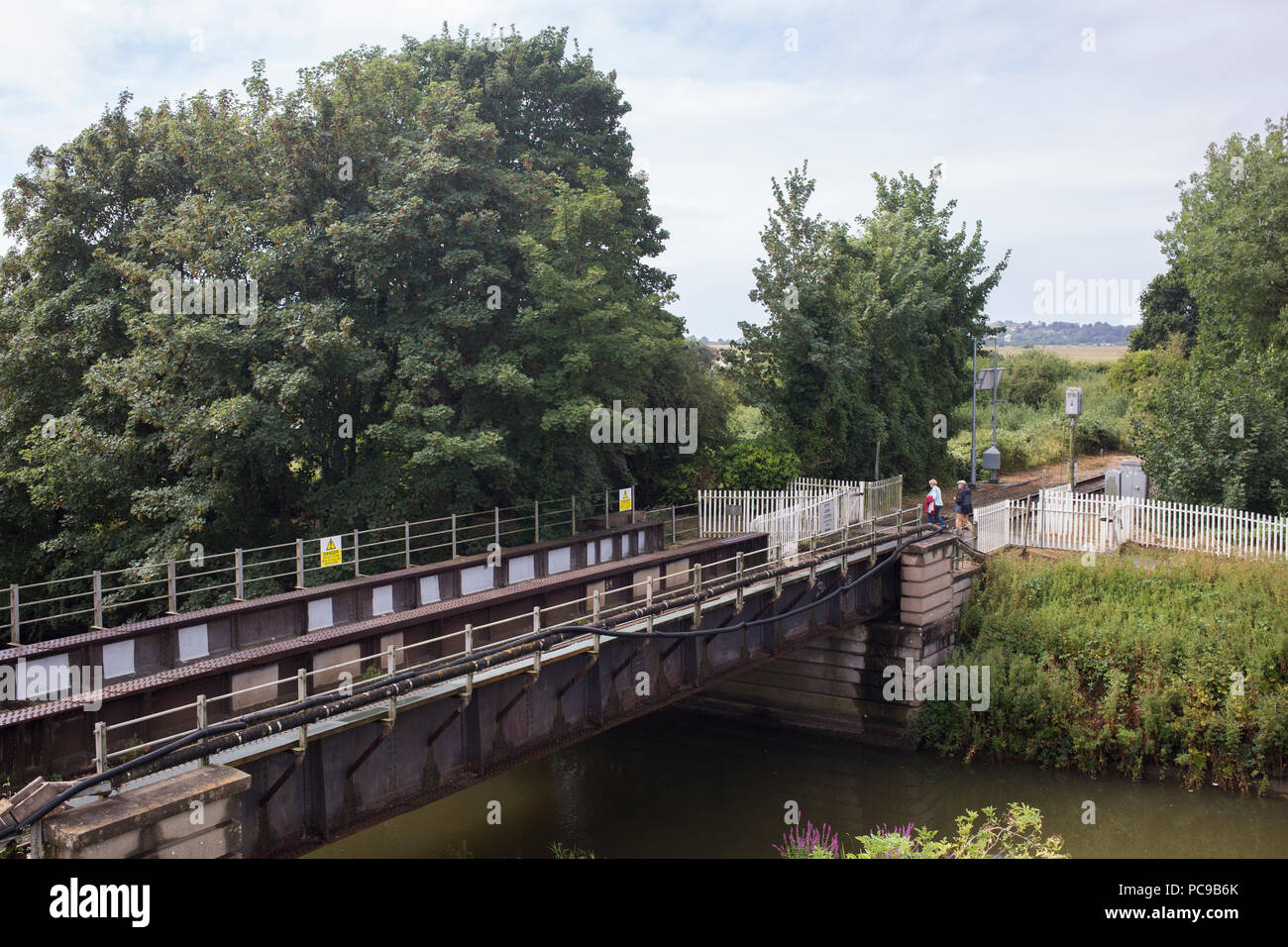 A senior couple walking across an unmanned railway level crossing, by a ...