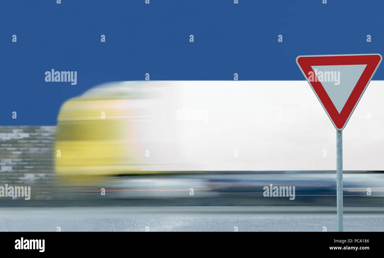 Give way yield road sign, motion blurred truck vehicle traffic ...