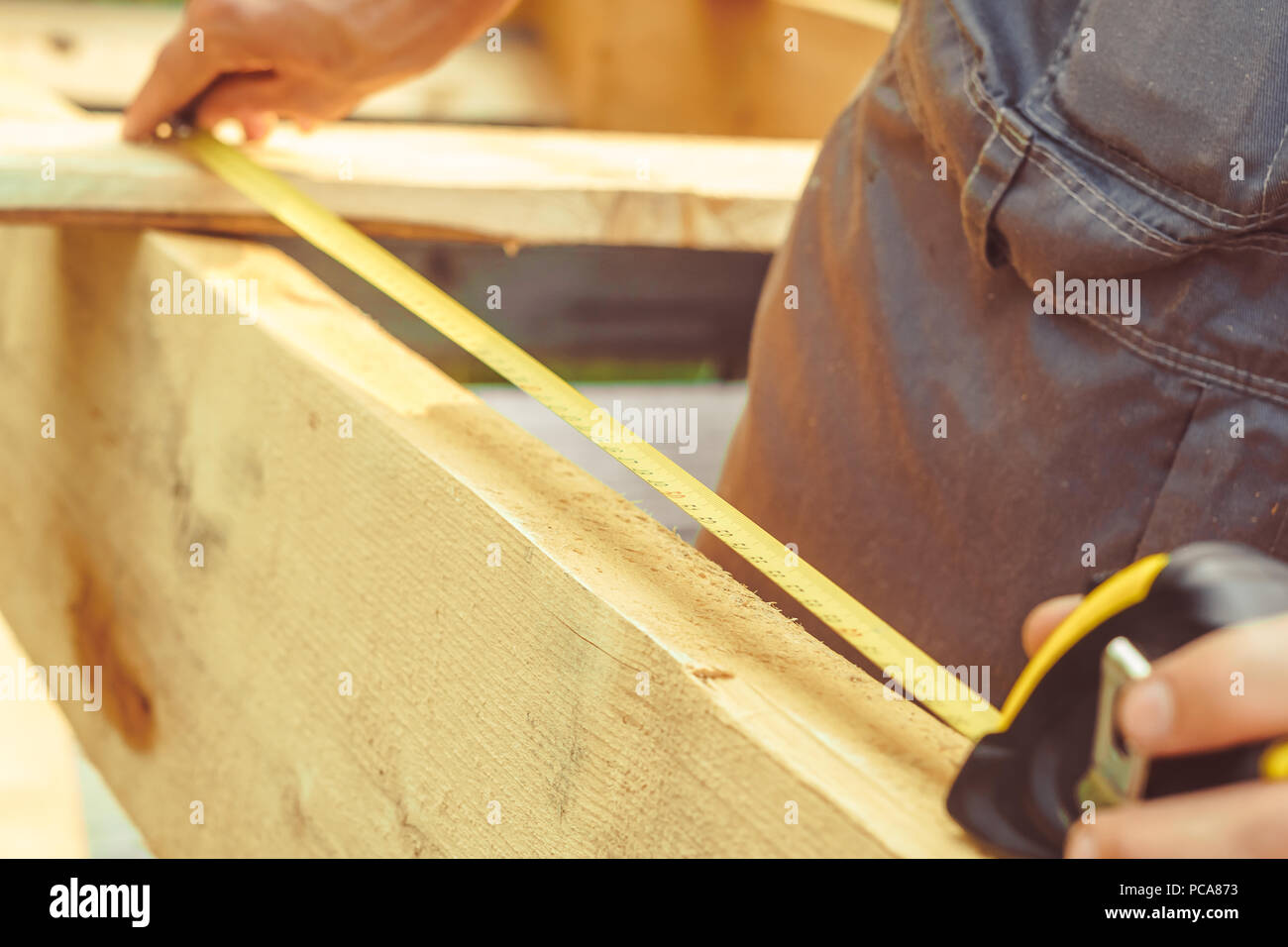 The worker makes measurements of a board with the help of a ruler, a ...