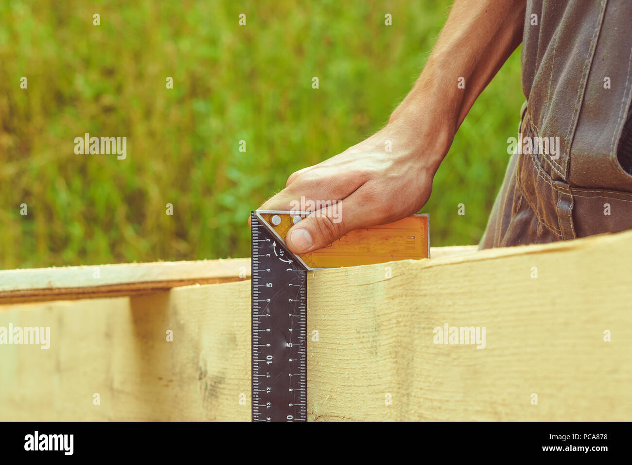 The worker makes measurements of a board with the help of a ruler, a ...