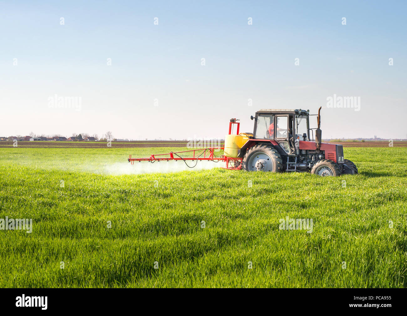 Tractor spraying wheat field with sprayer Stock Photo - Alamy