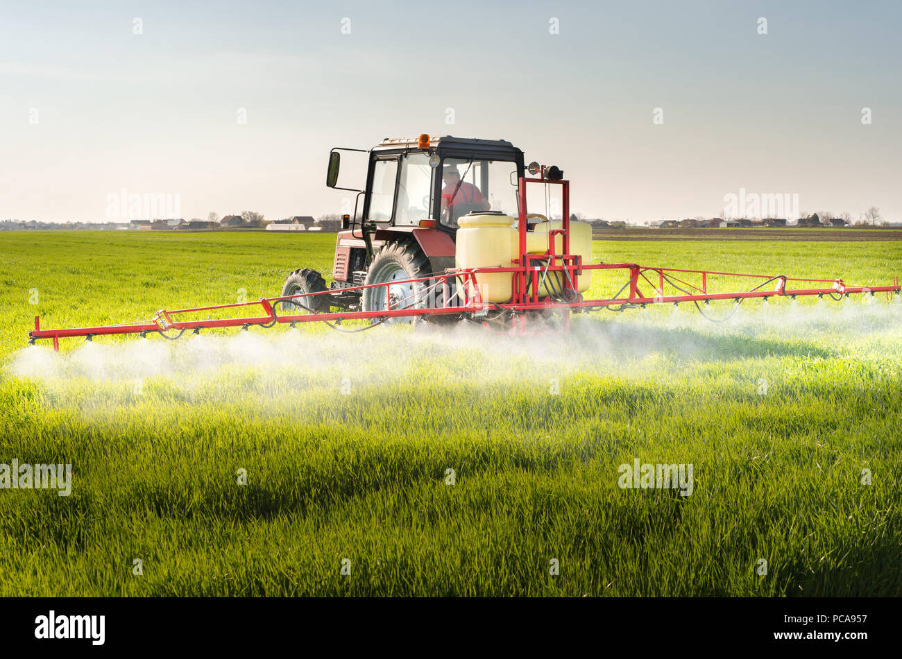 Tractor spraying wheat field with sprayer Stock Photo - Alamy