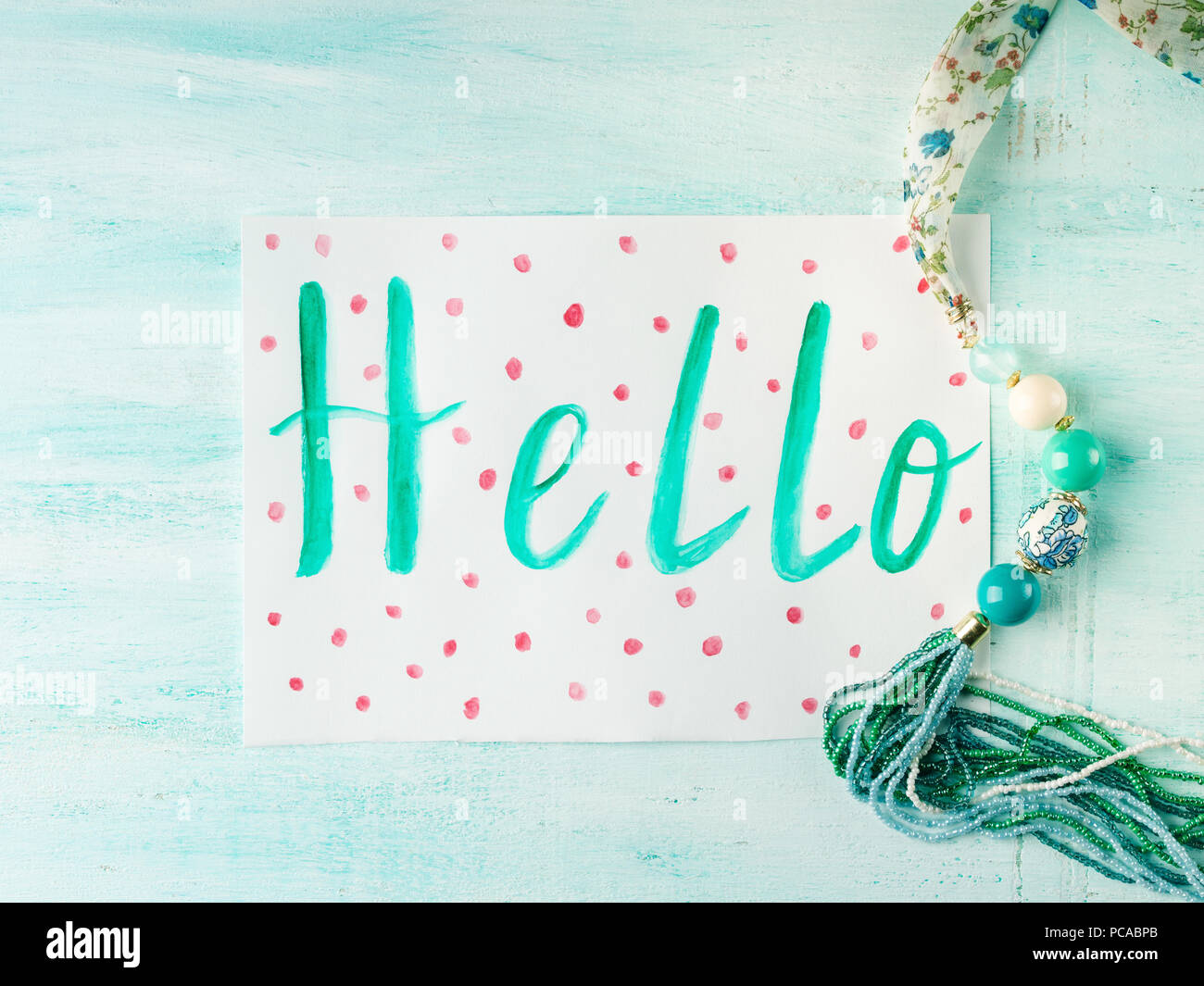 Hello card on pastel turquoise background with necklace Stock Photo - Alamy