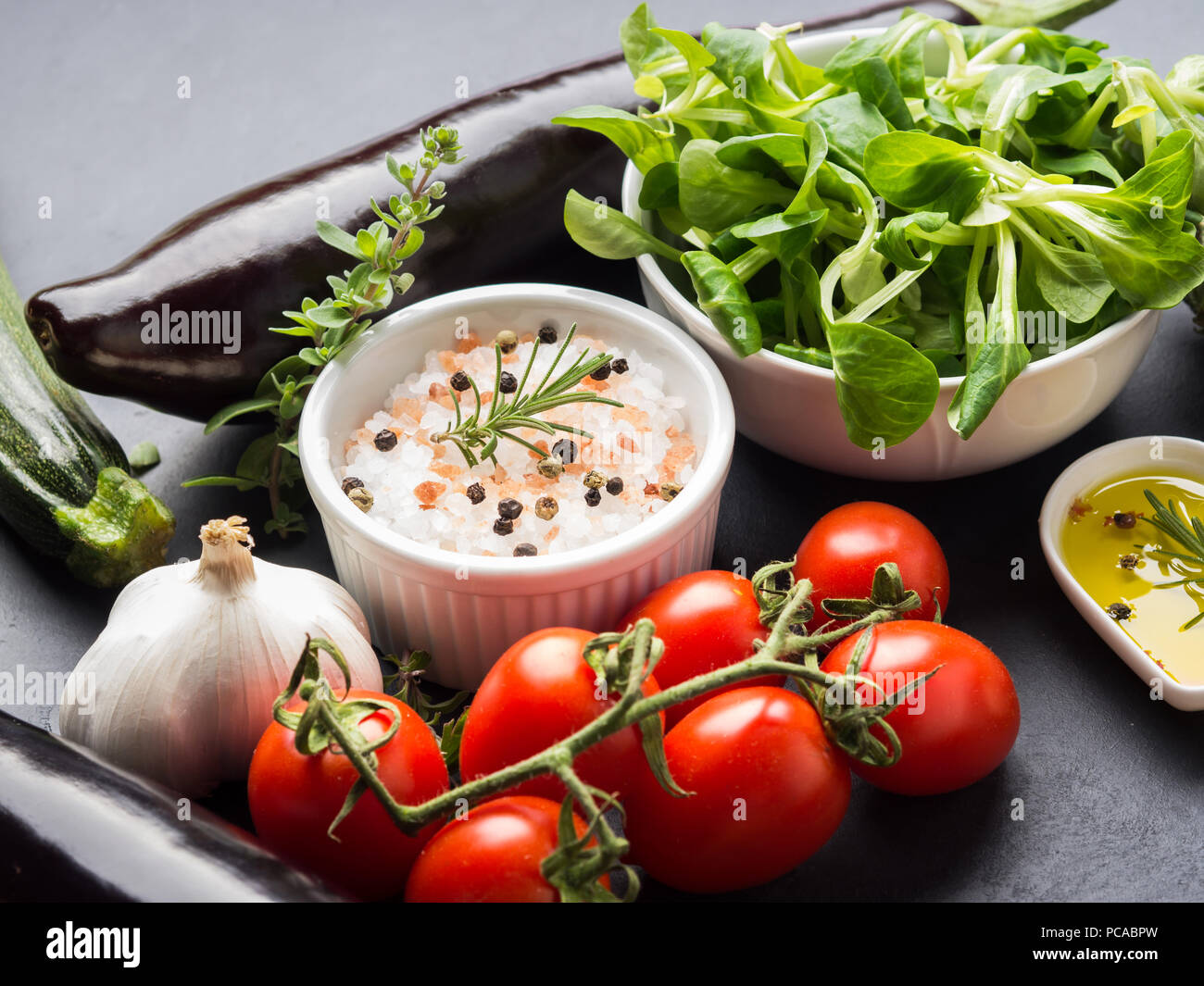 Mix of raw vegetables with salt, spices on dark background. Clean ...