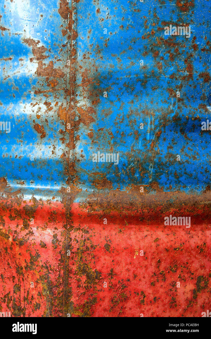 The wall of metal barrels painted red and blue paint with rust traces ...
