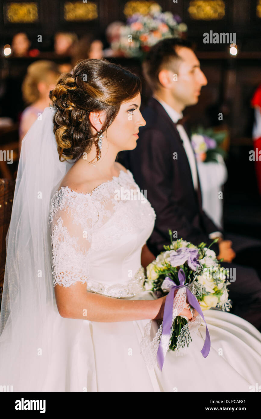 Wedding ceremony. Side view of the newlyweds. Bride holds the wedding ...