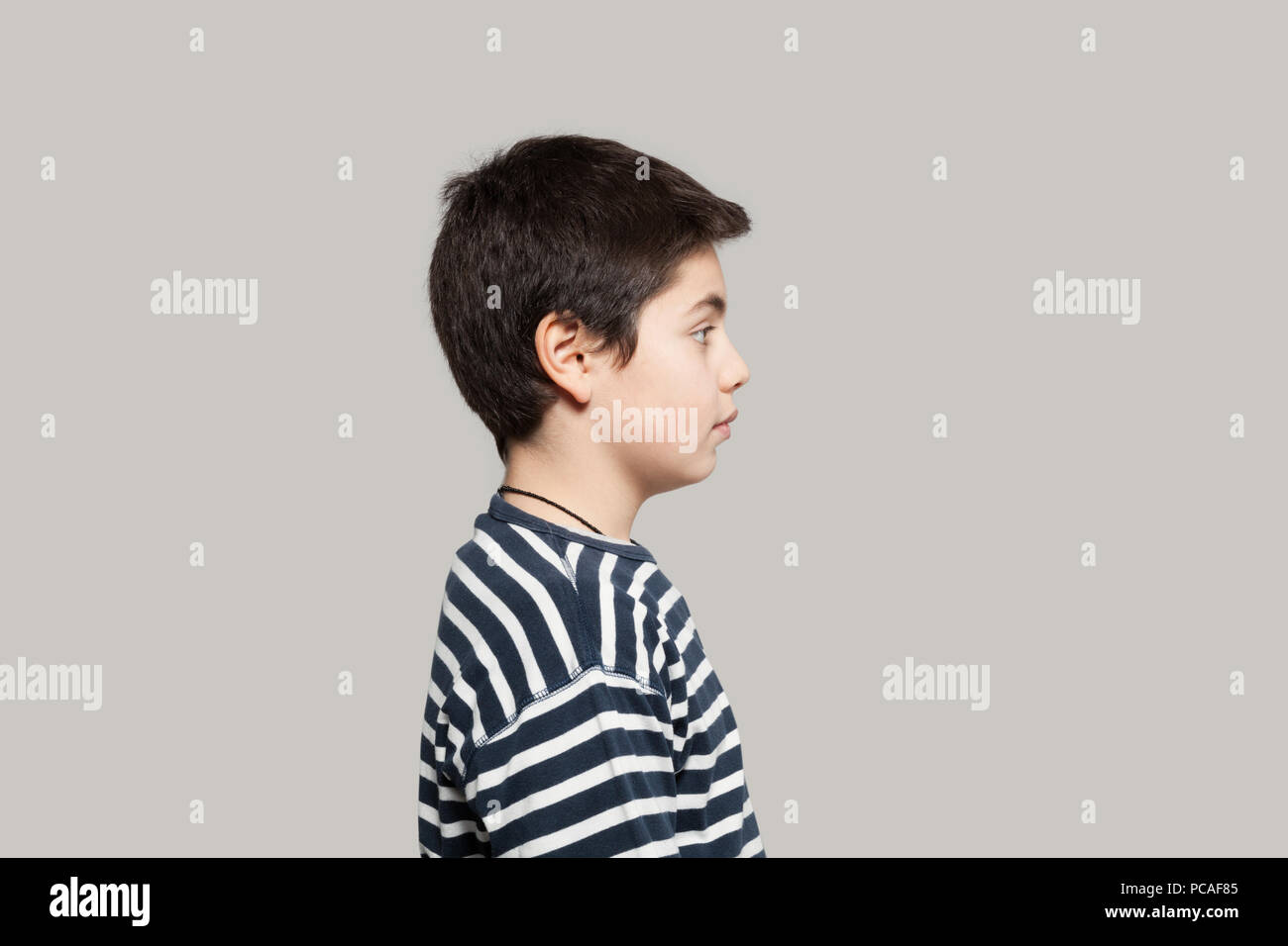 Sweet boy wearing striped shirt, profile view. Portrait on grey ...