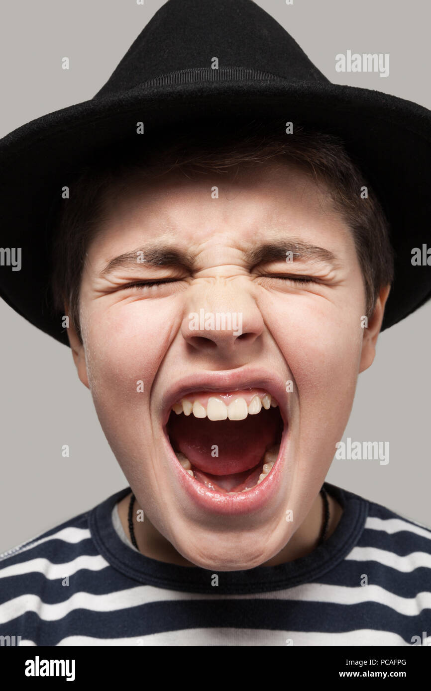 Boy with hat laughs amused, portrait in studio Stock Photo - Alamy