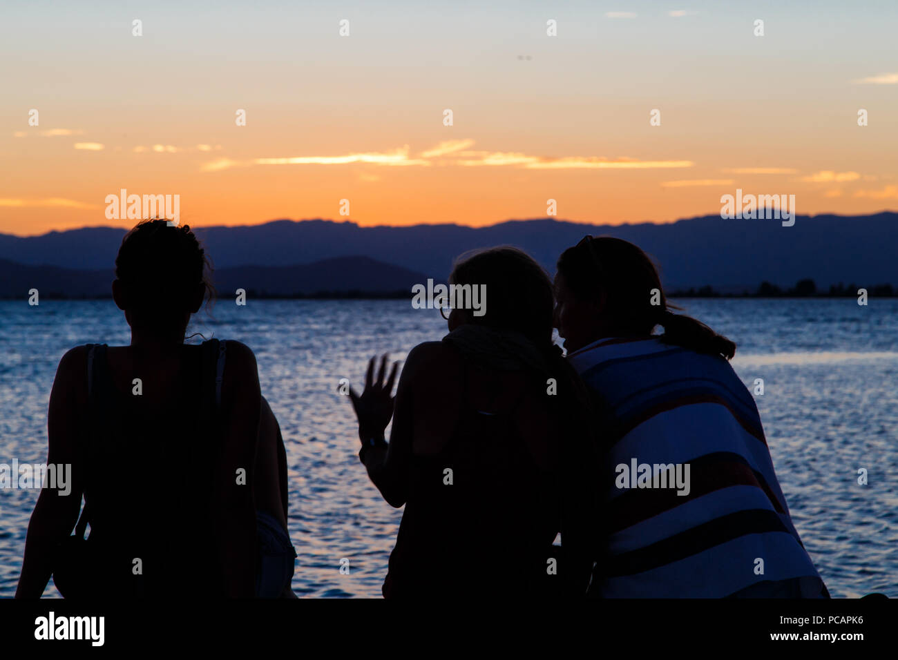 people on their backs watching sunset on the beach Stock Photo - Alamy