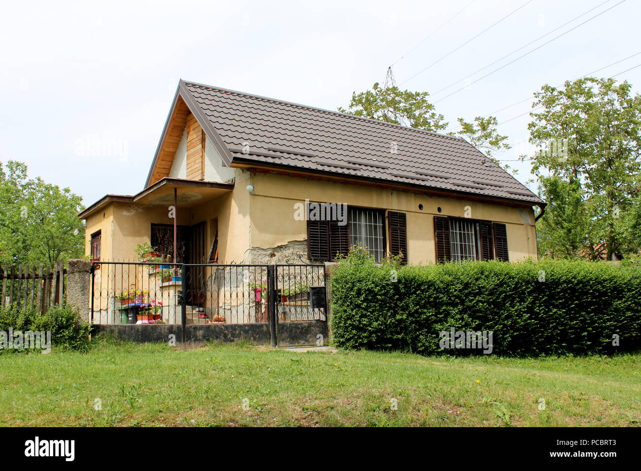 Small family house with dilapidated facade, metal bars and wooden window blinds, entrance full ...