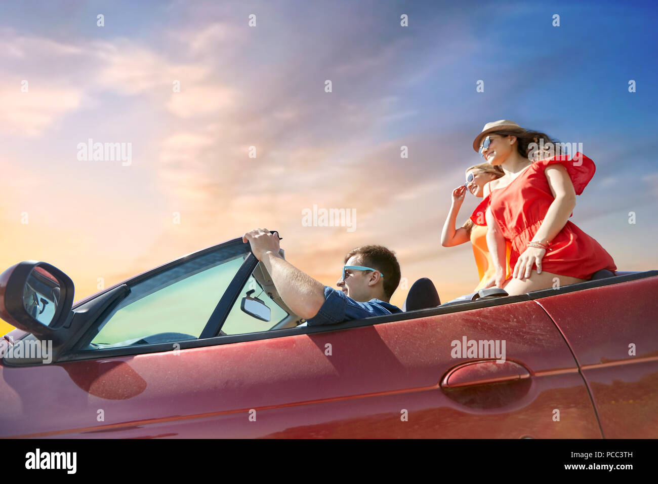 happy friends driving in convertible car over sky Stock Photo - Alamy