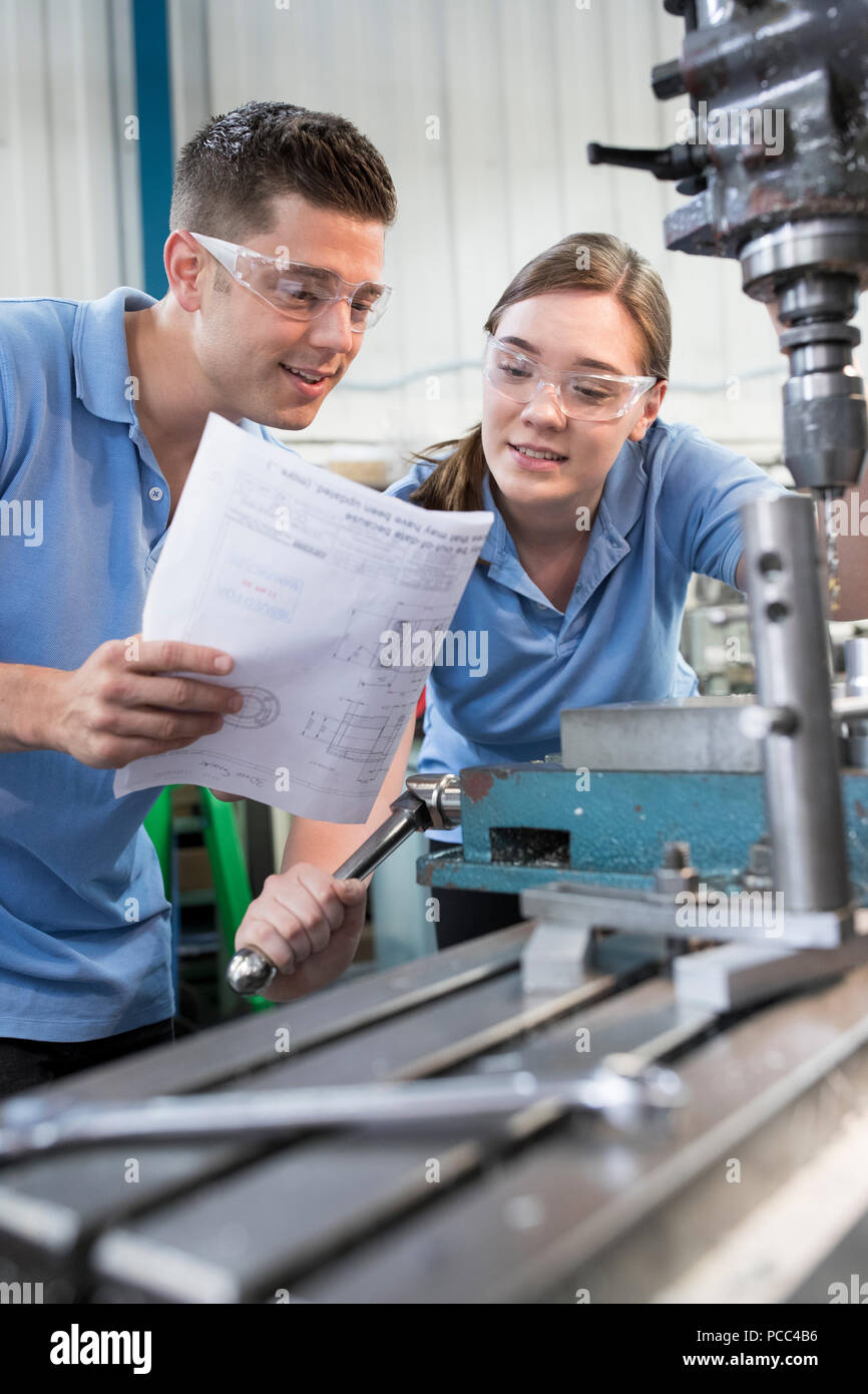 Engineer Instructing Female Apprentice On Use Of Drill Stock Photo - Alamy