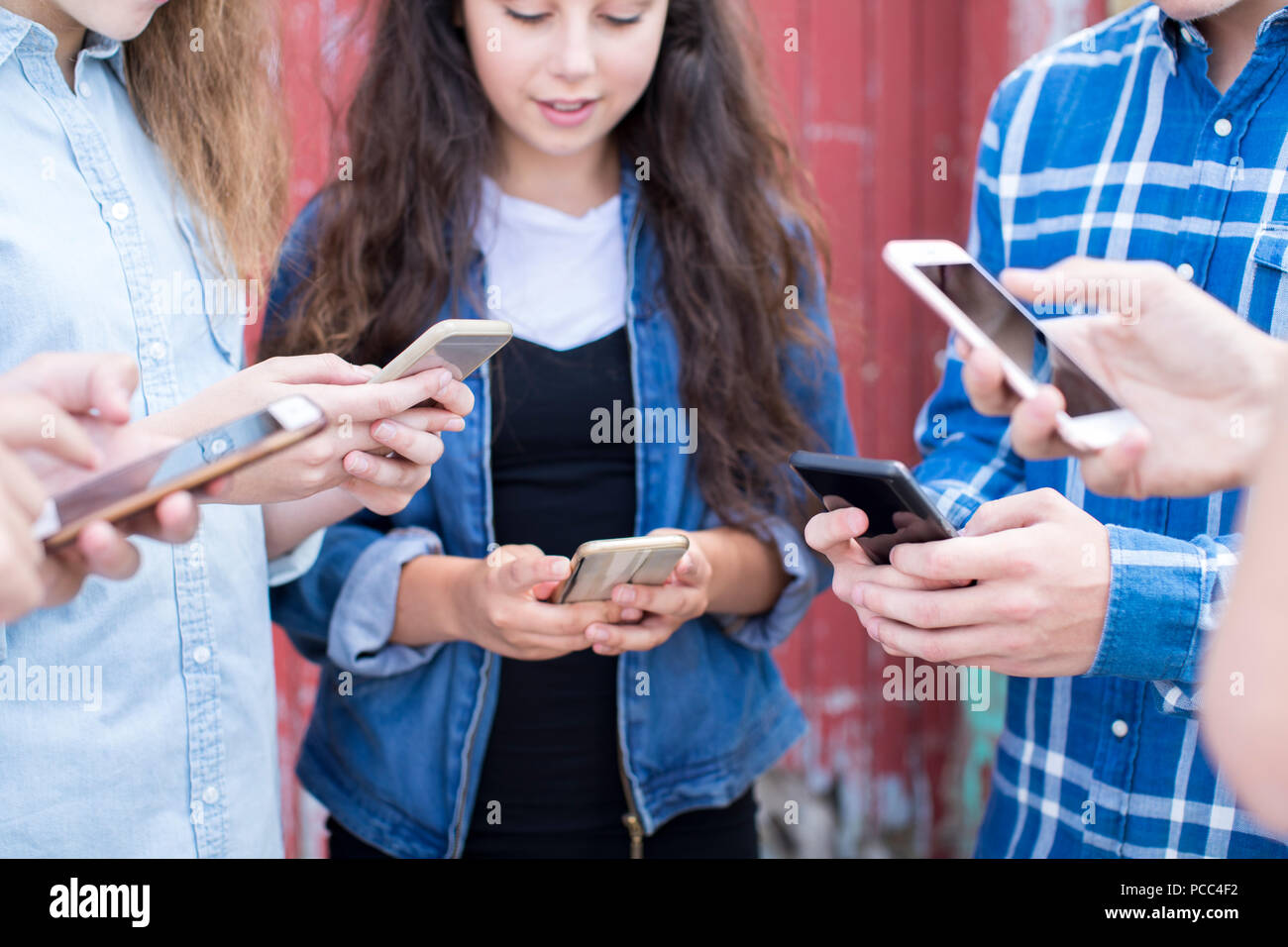 Close Up Of Group Of Teenage Friends Looking At Mobile Phones In Urban ...