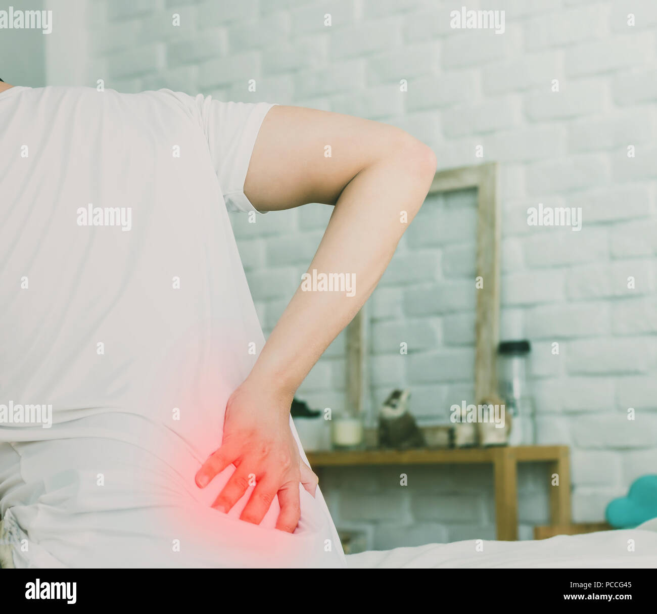 Asian man back pain and sit on bed in bedroom in the morning.color tone ...