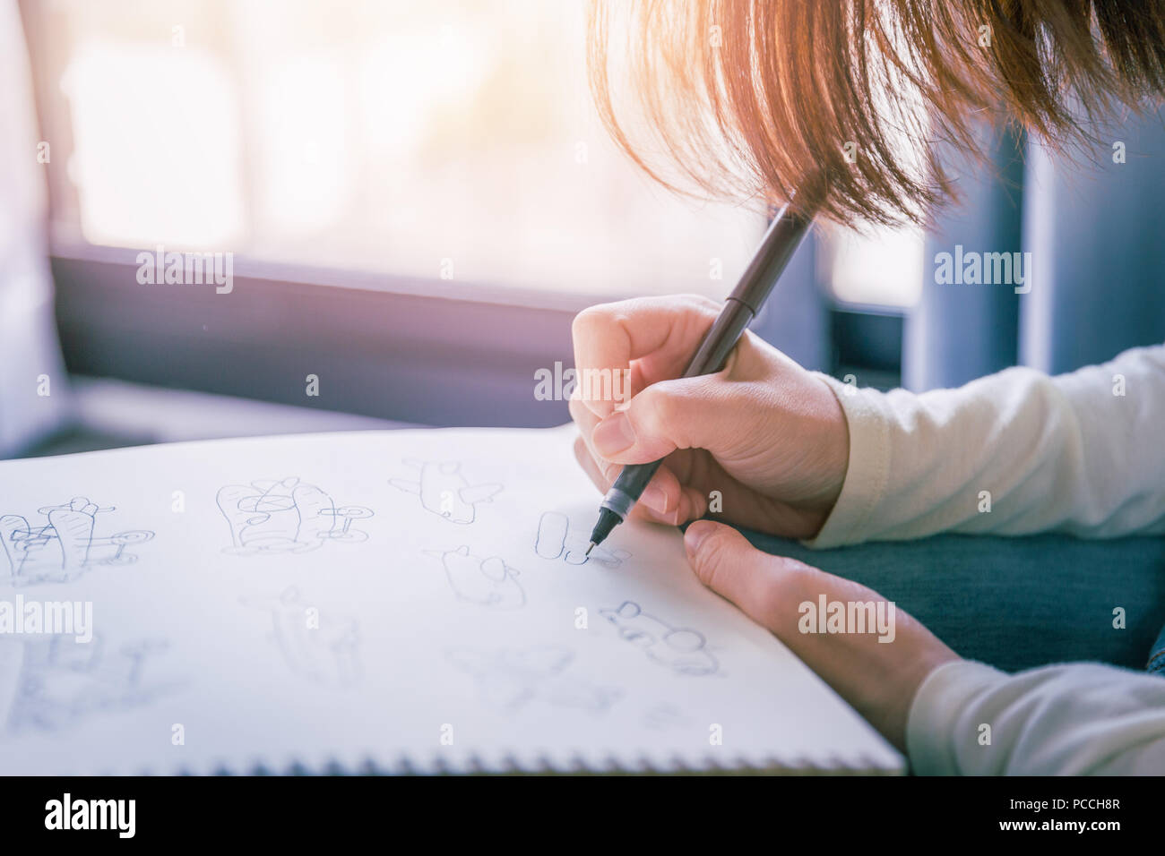 Woman performs free-hand ink pen drawing the artworks on white paper in ...