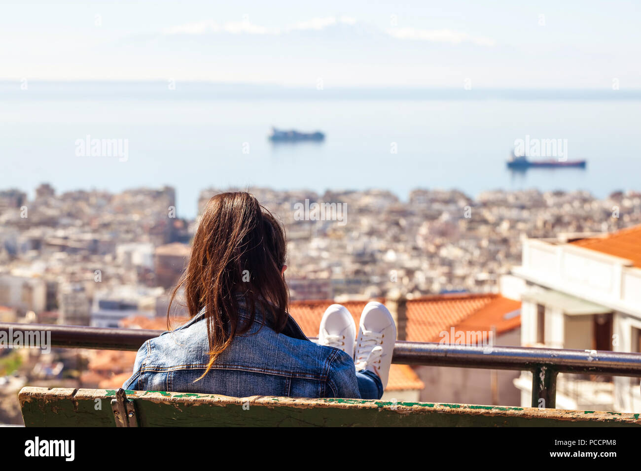 Girl sitting on a bench looking at the gulf in Thessaloniki, Greece ...