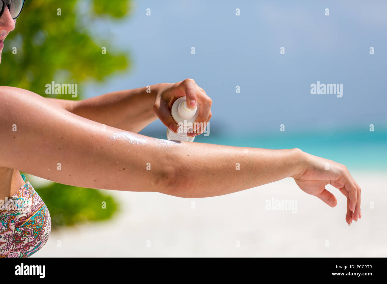 woman putting on lotion on her skin at the beach Stock Photo - Alamy