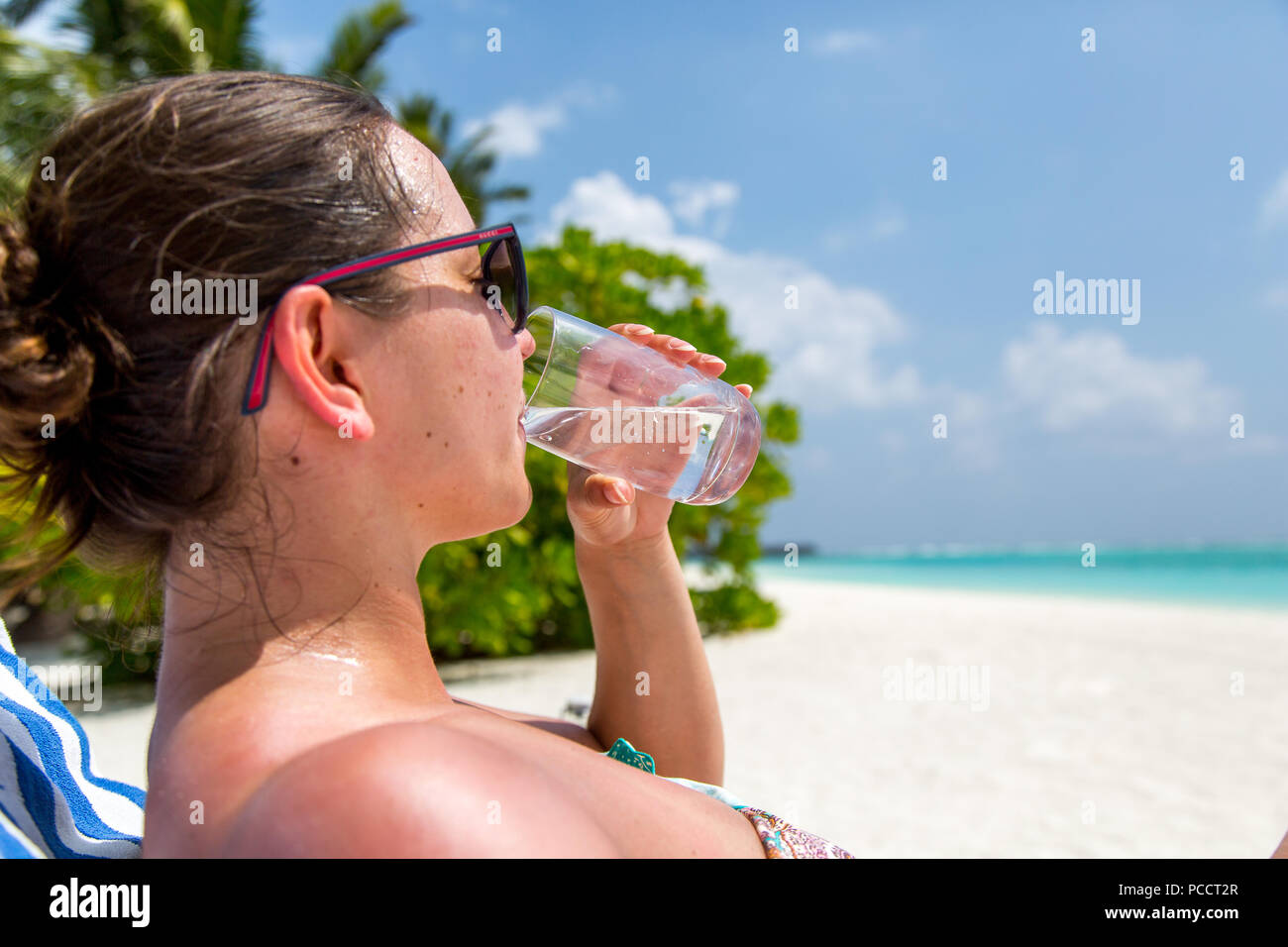 woman putting on lotion on her skin at the beach Stock Photo - Alamy