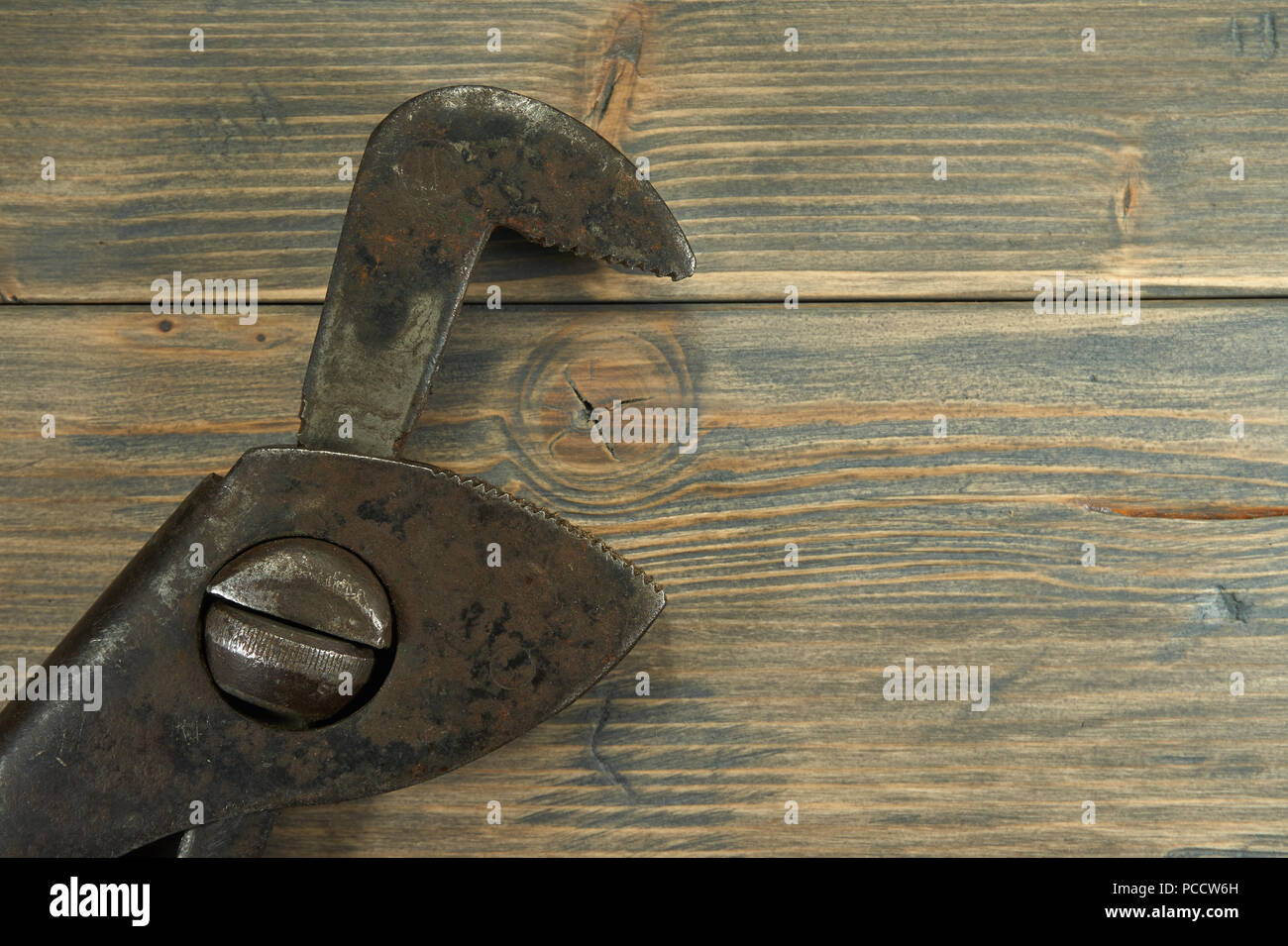 Vintage rusty pipe wrench on a weathered wood background. Plumbing ...