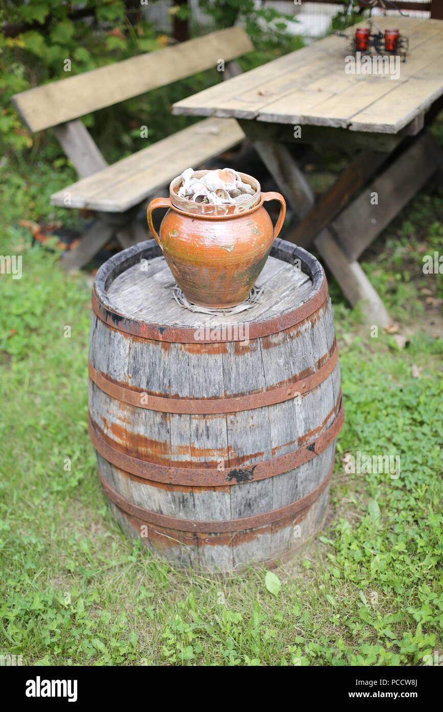 Clay pot filled with empty sea snails shells on a rusty old barrel in ...