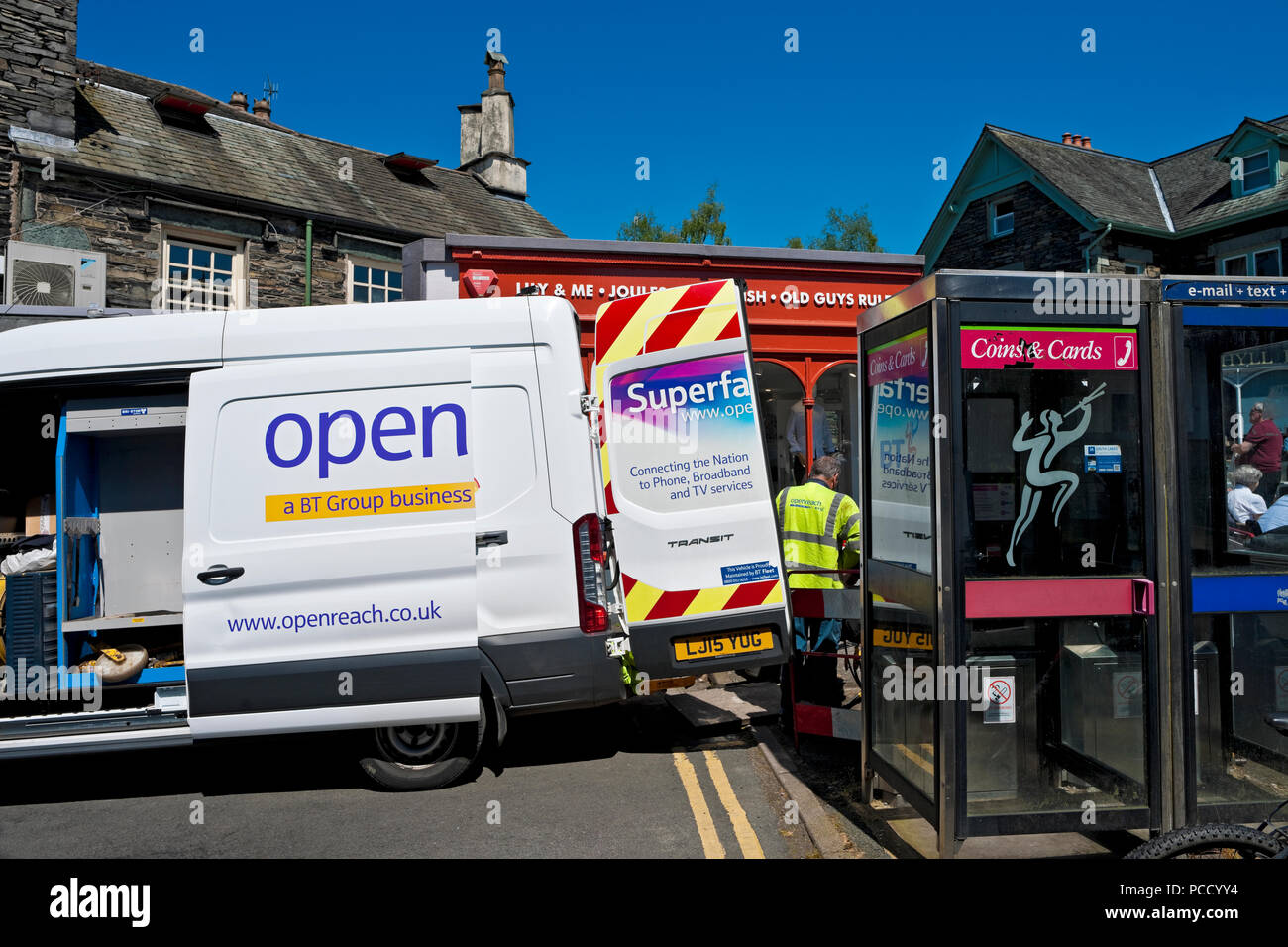Openreach engineer worker and van outside a telephone phone box ...