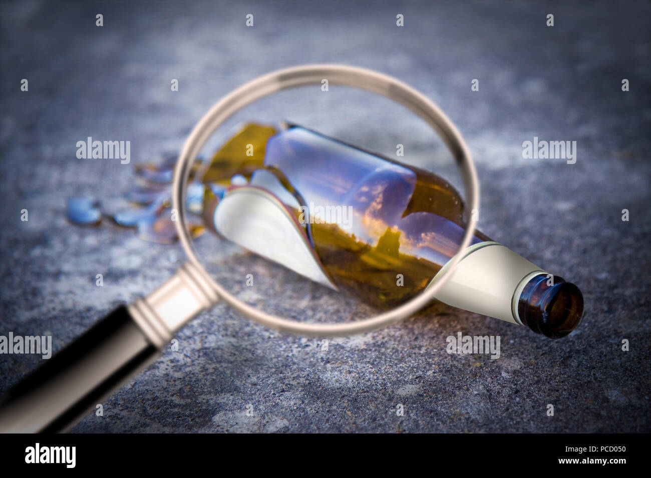 Shattered beer bottle resting on the ground seen through a magnifying ...