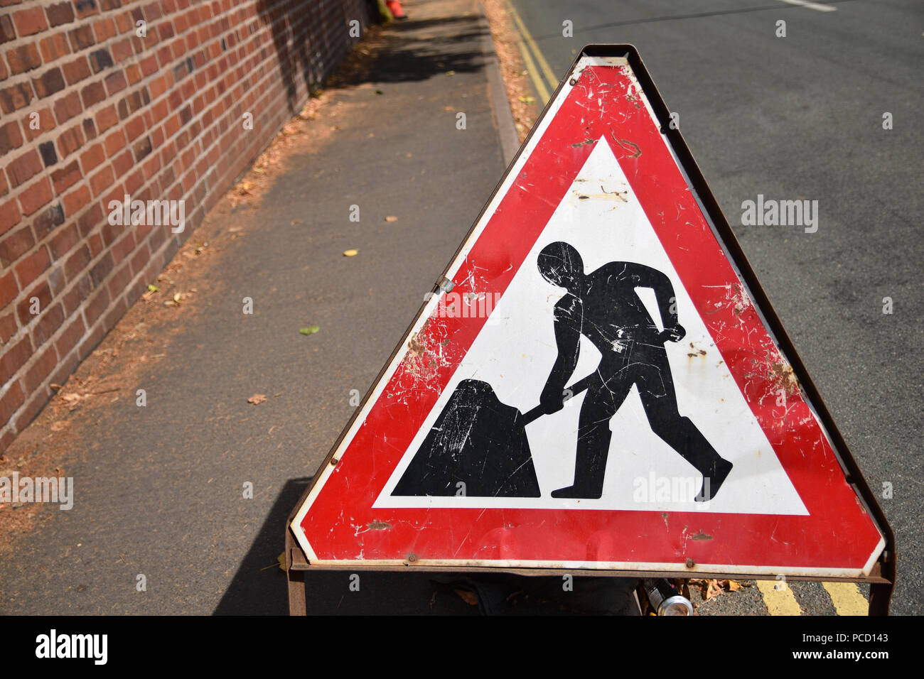 Old, weathered, red and white triangular road safety sign Men At Work ...