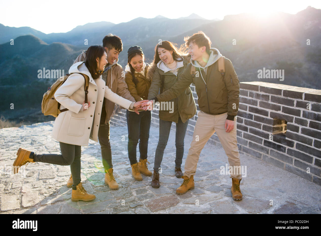 Happy young Chinese friends stacking hands on the Great Wall Stock ...